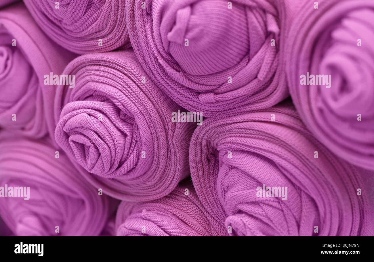 Knitted pink fabric rolled into rolls, close up shot, abstract textile ...
