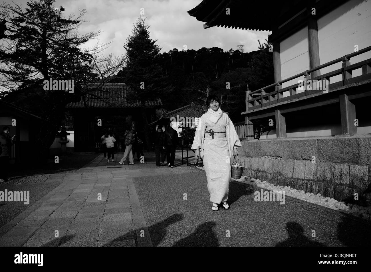 Woman in kimono walks through Kiyomizu-dera’s grounds, her figure lit ...