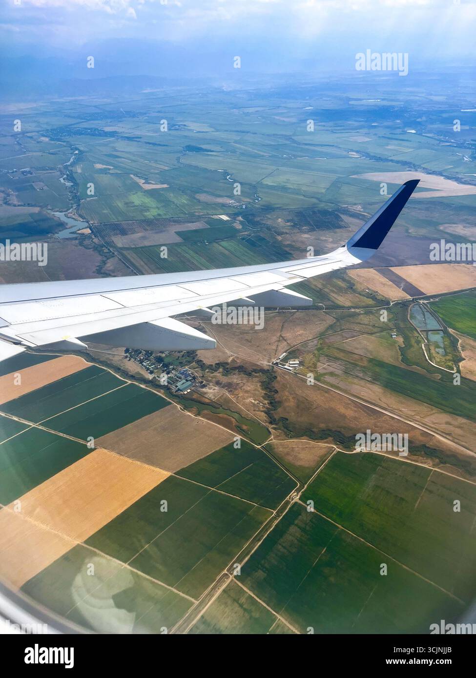 View from airplane window with wing and green fields Stock Photo - Alamy