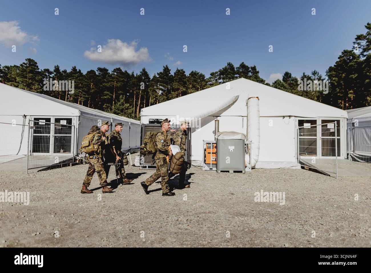 Soldiers walk past the accommodation tents with luggage, taken at the ...