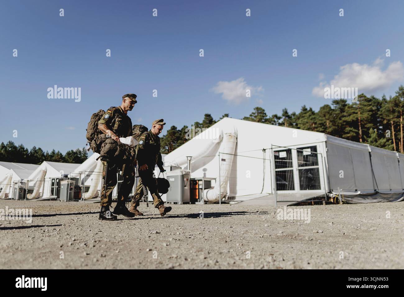 Soldiers walk past the accommodation tents with luggage, taken at the ...