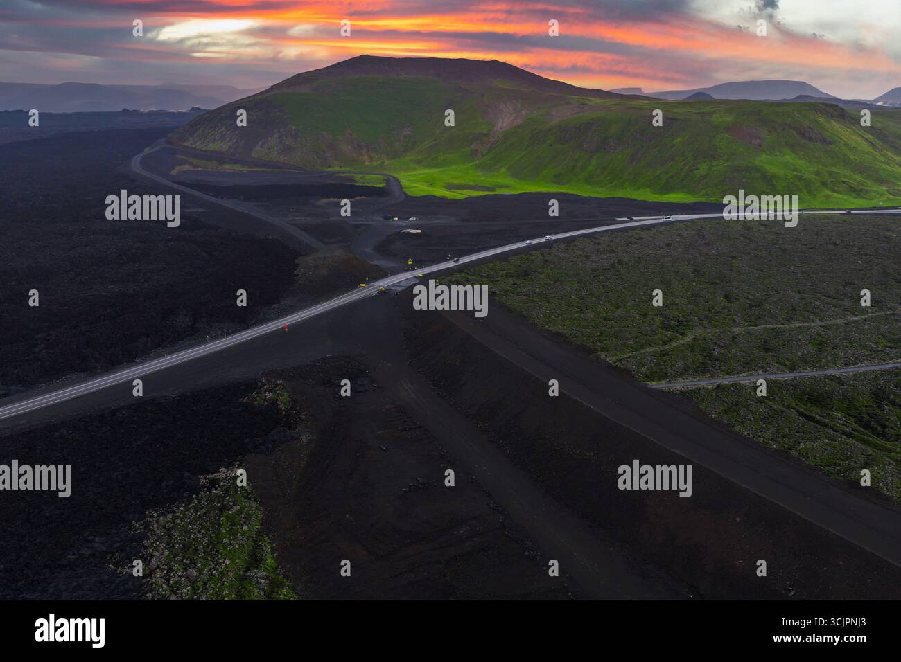 Aerial perspective of dark lava fields meeting vibrant green hills in ...