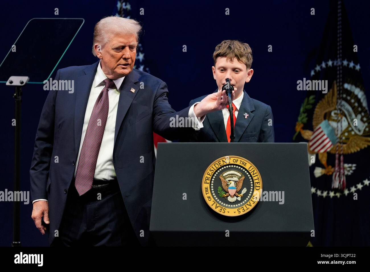 President Donald Trump adjusts a mic for Shea Encinas, as he speaks to ...