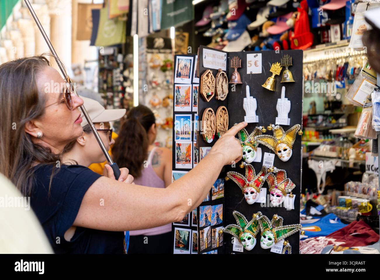 Woman shows to Souvenir magnets from Italy on the street. Middle finger ...