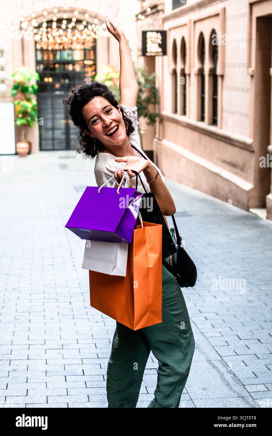 Happy shopper holding shopping bags and raising an arm Stock Photo - Alamy