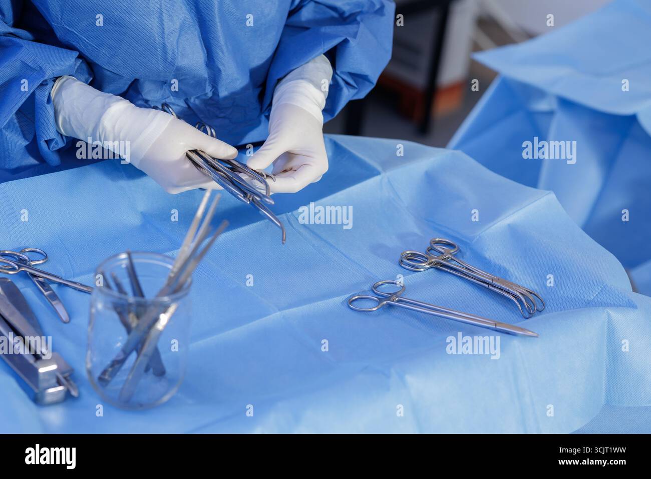 Medical staff arrange stainless tools on a blue sterile field for ...