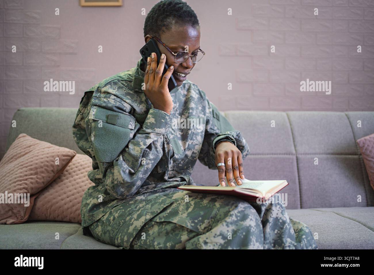 Smiling african american soldier talking on smartphone and reading book ...