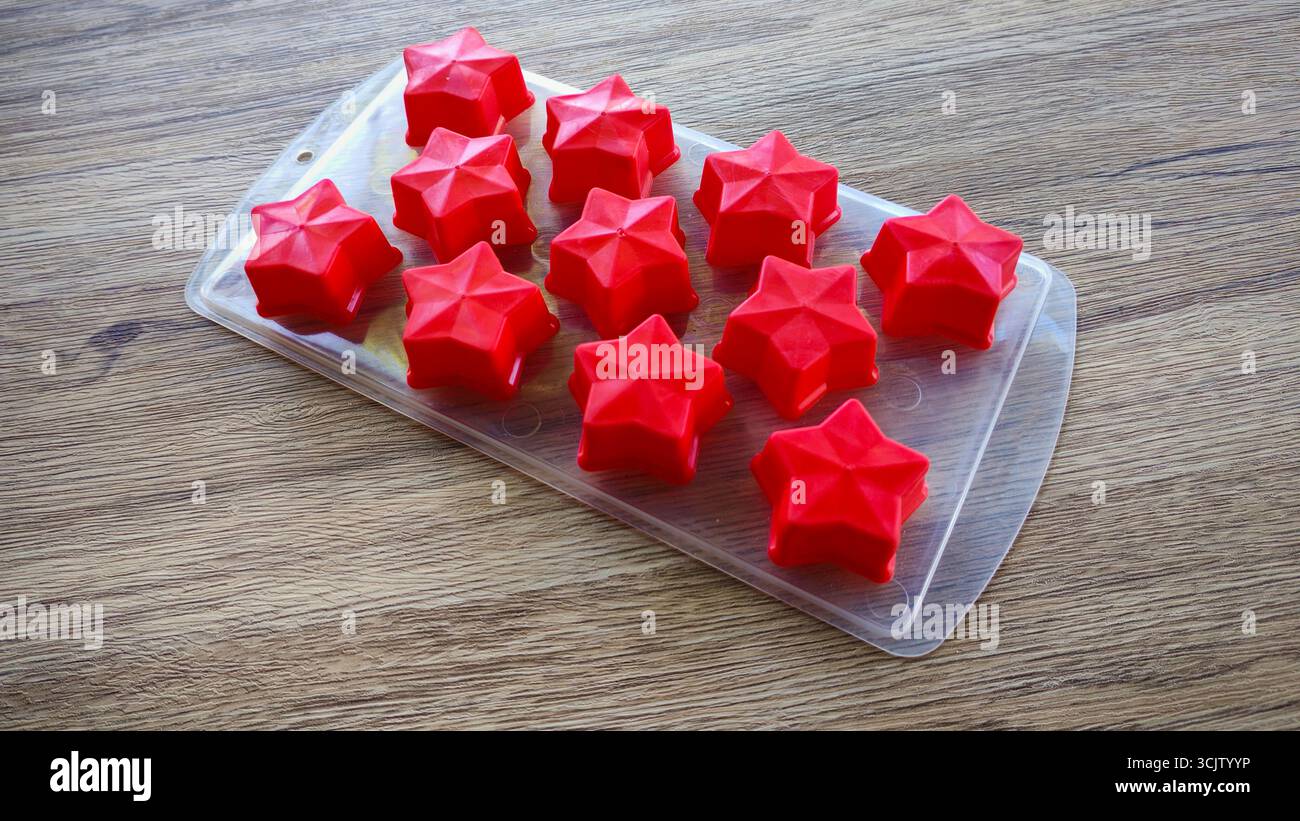 Empty red silicone star molds in a transparent tray on a wooden table ...