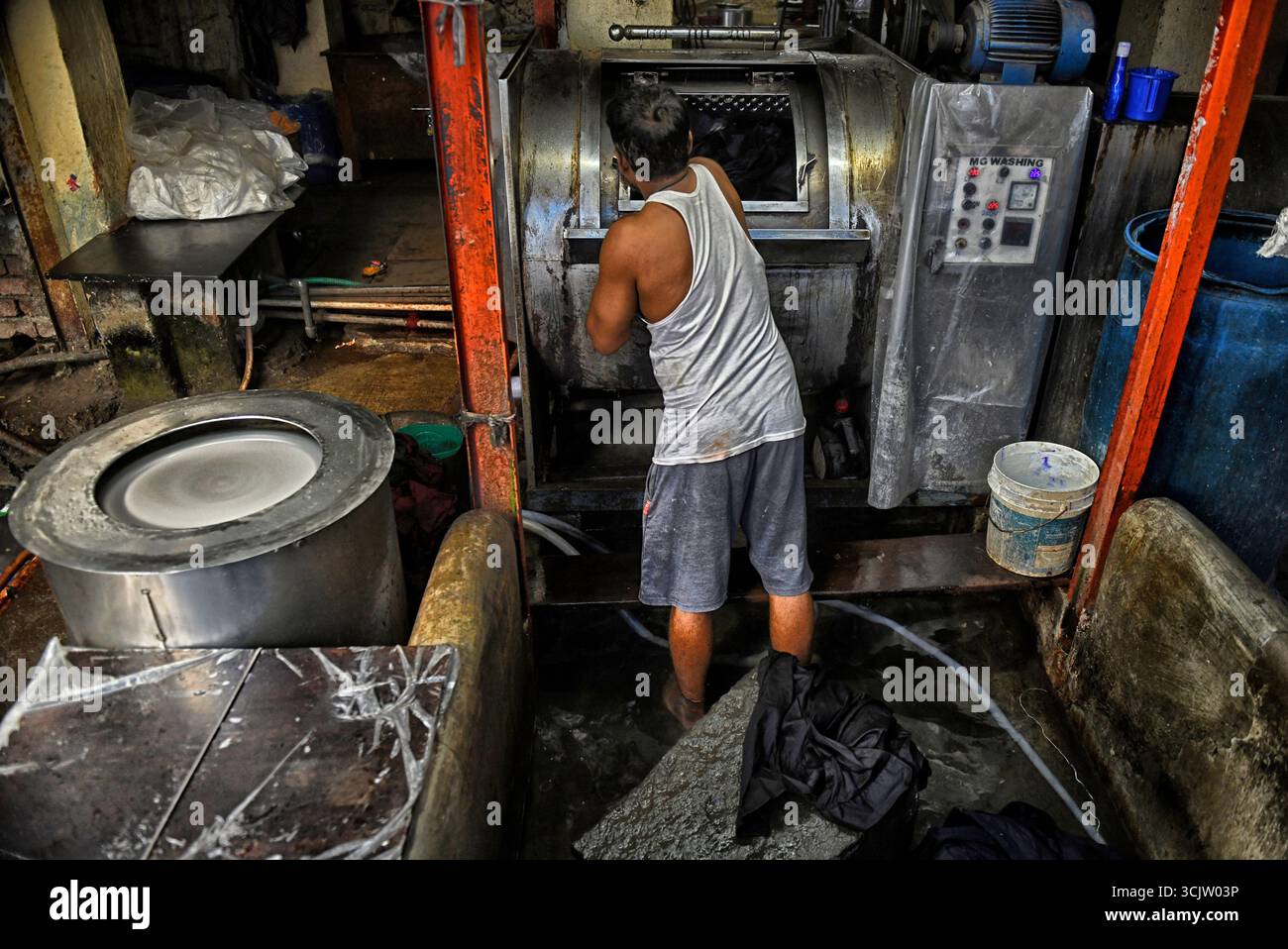 A worker is seen busy in washing out clothes in a big size washing ...