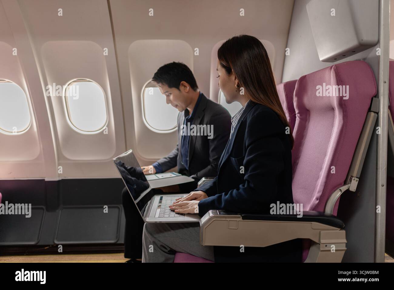 A business man and woman in formal suits working together on a flight ...