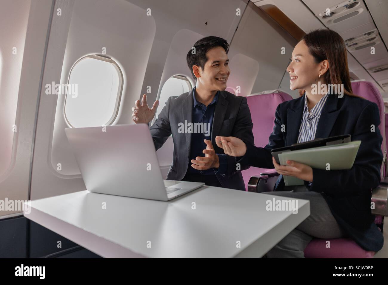 A business man and woman in formal suits working together on a flight ...