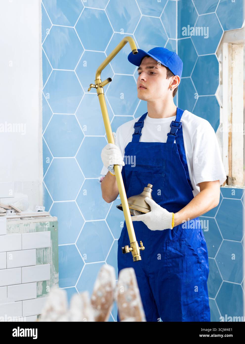 Young contractor preparing shower for installation in building under ...