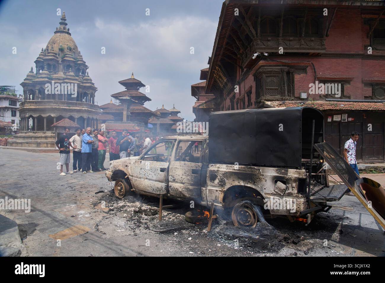 People look at a burnt police vehicle during protests against social ...