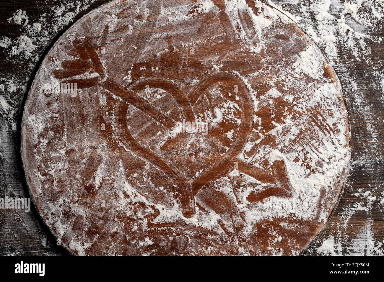 Drawing of heart with arrow on pizza board with white flour, close up ...