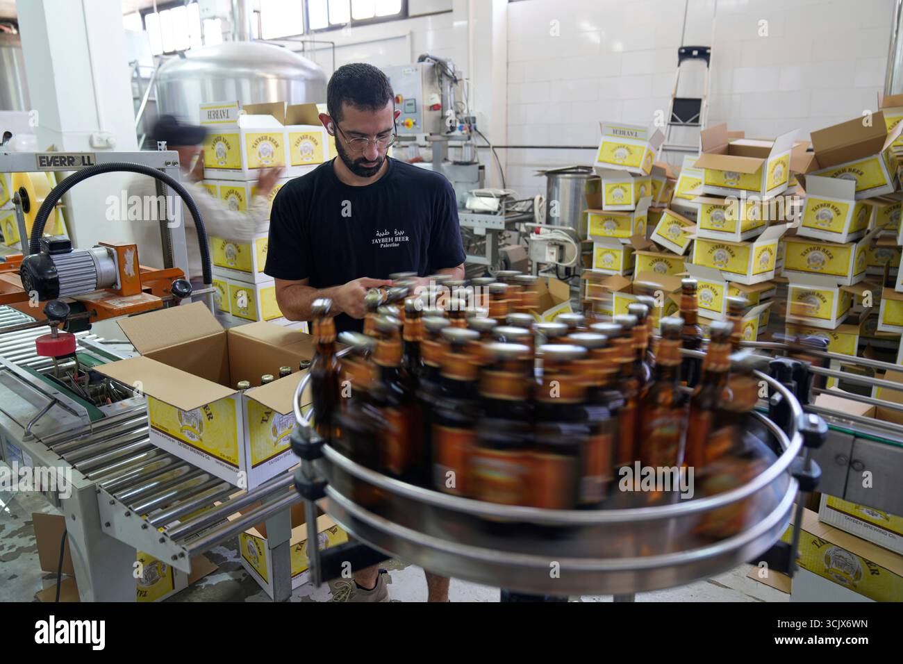 Canaan Khoury packs Taybeh beer bottles into boxes on a production line ...
