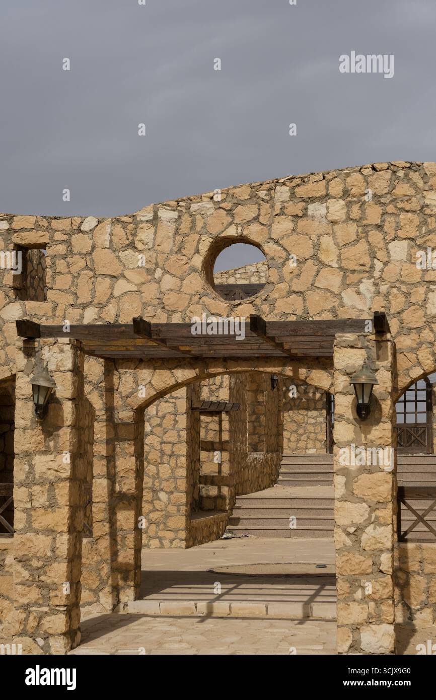 View of stone arches and pergolas create a textured pathway under a ...