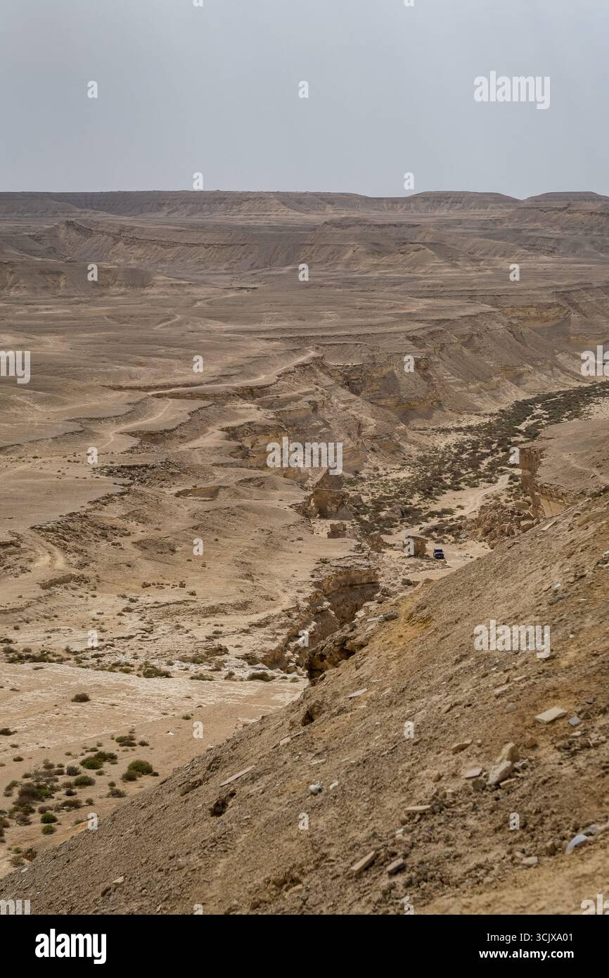 View of sun-baked desert landscape with rugged terrain and sparse ...