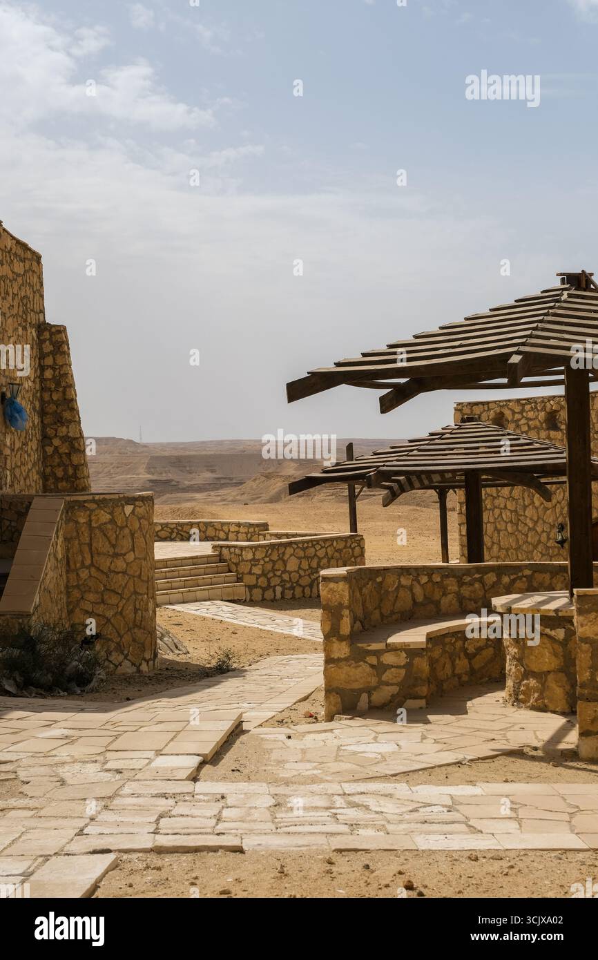 View of arid landscape with stone structures and shaded seating areas ...