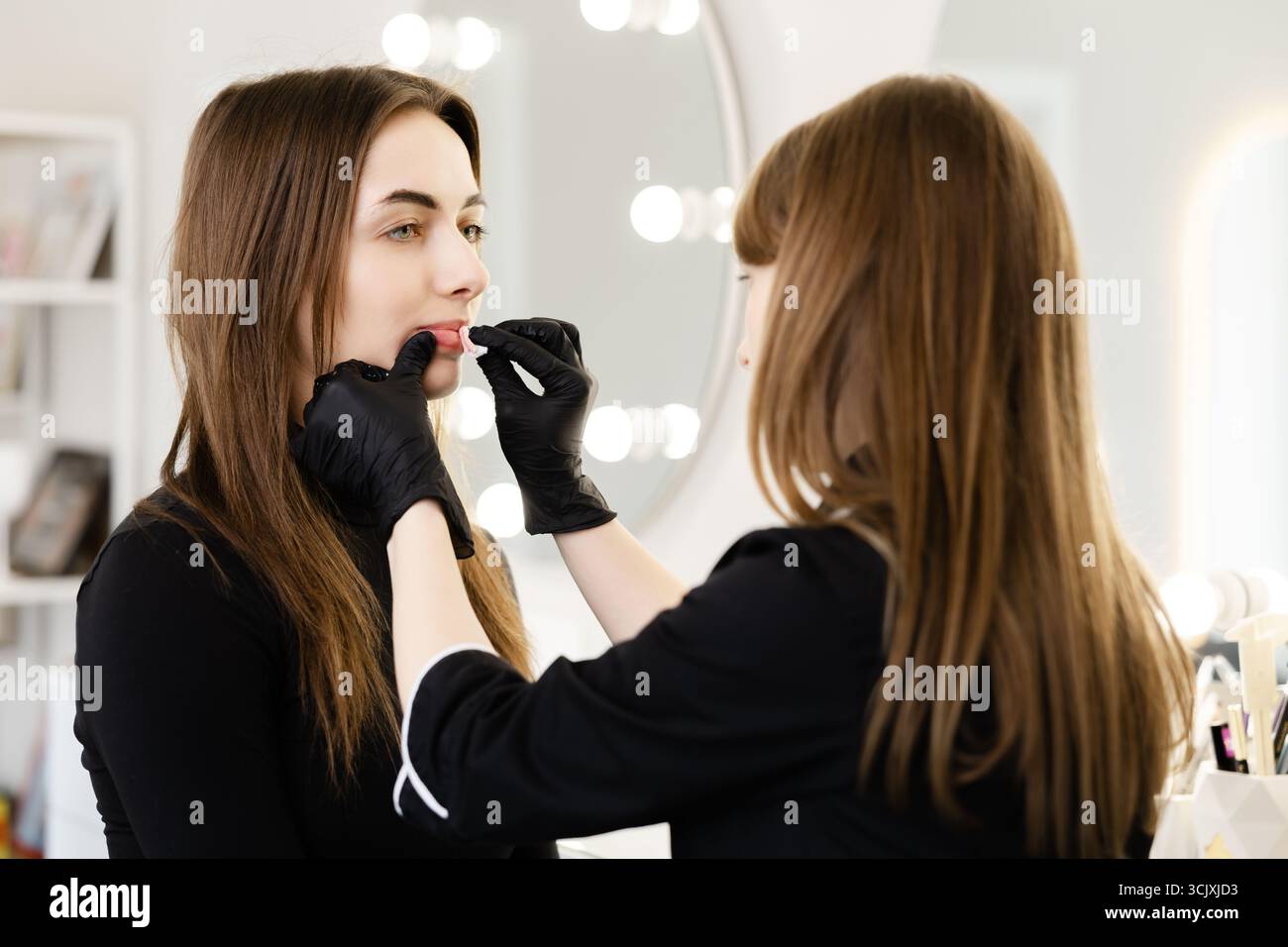 Professional makeup artist carefully applying lipstick to a client in a ...