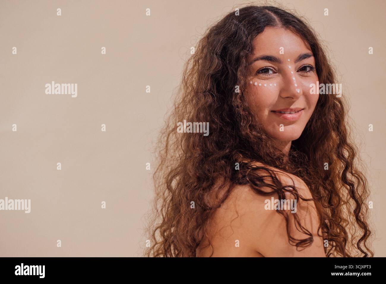 Smiling young woman with curly hair and artistic face paint, radiating ...