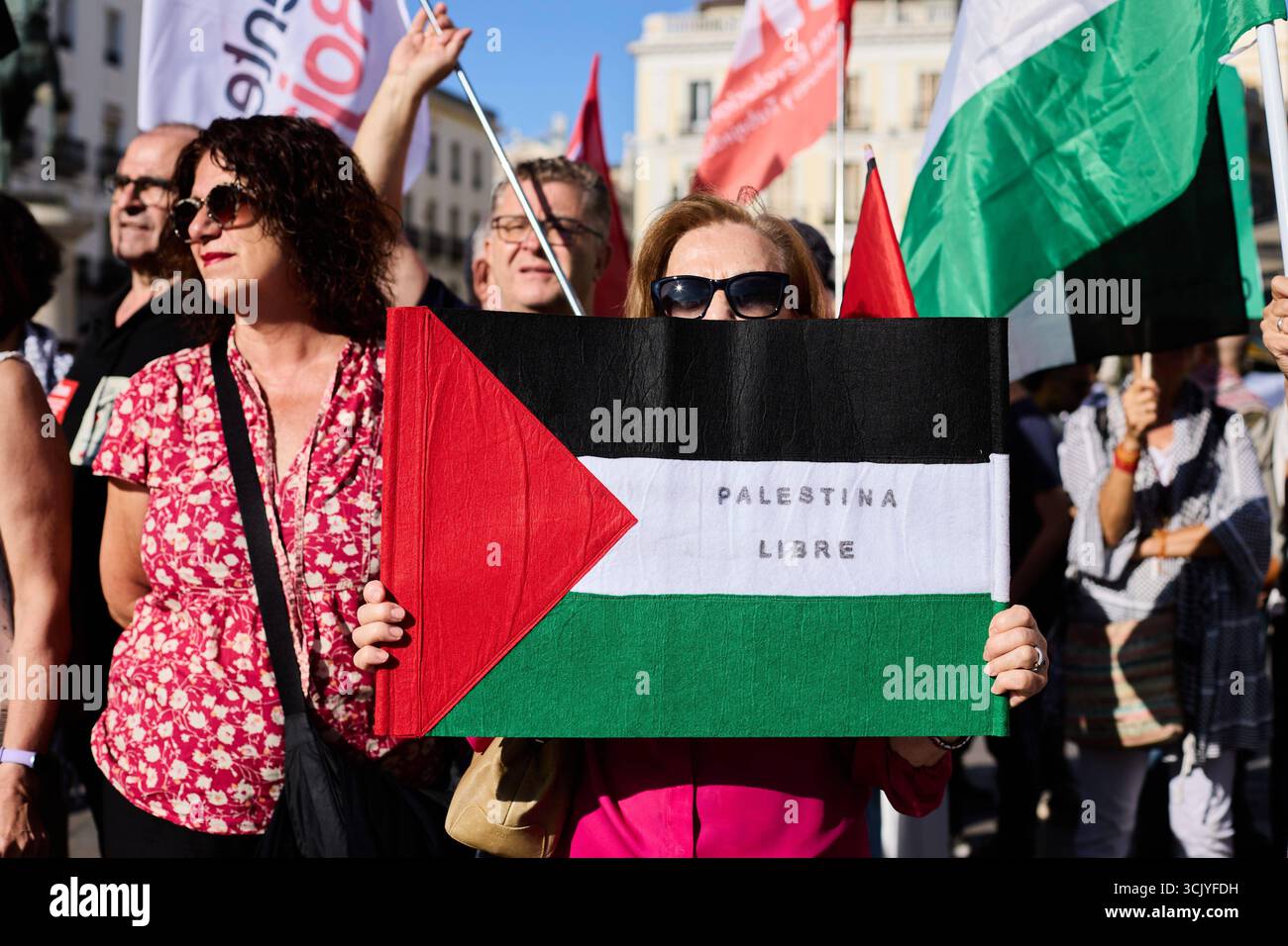 A woman holds a Palestinian flag with the message “Palestina libre ...