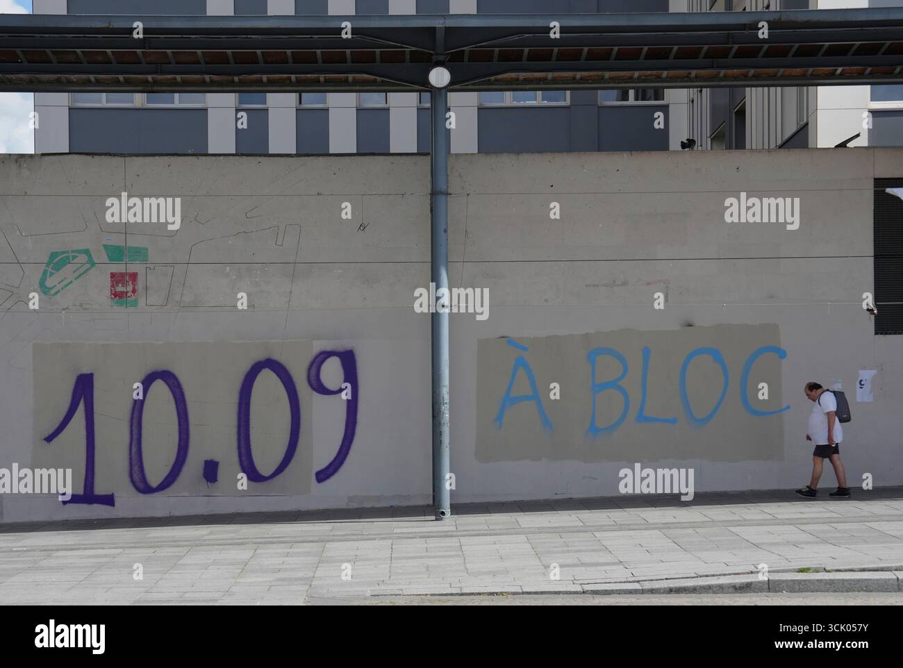 A man walks past a graffiti that reads, "September 10, all-out strike ...