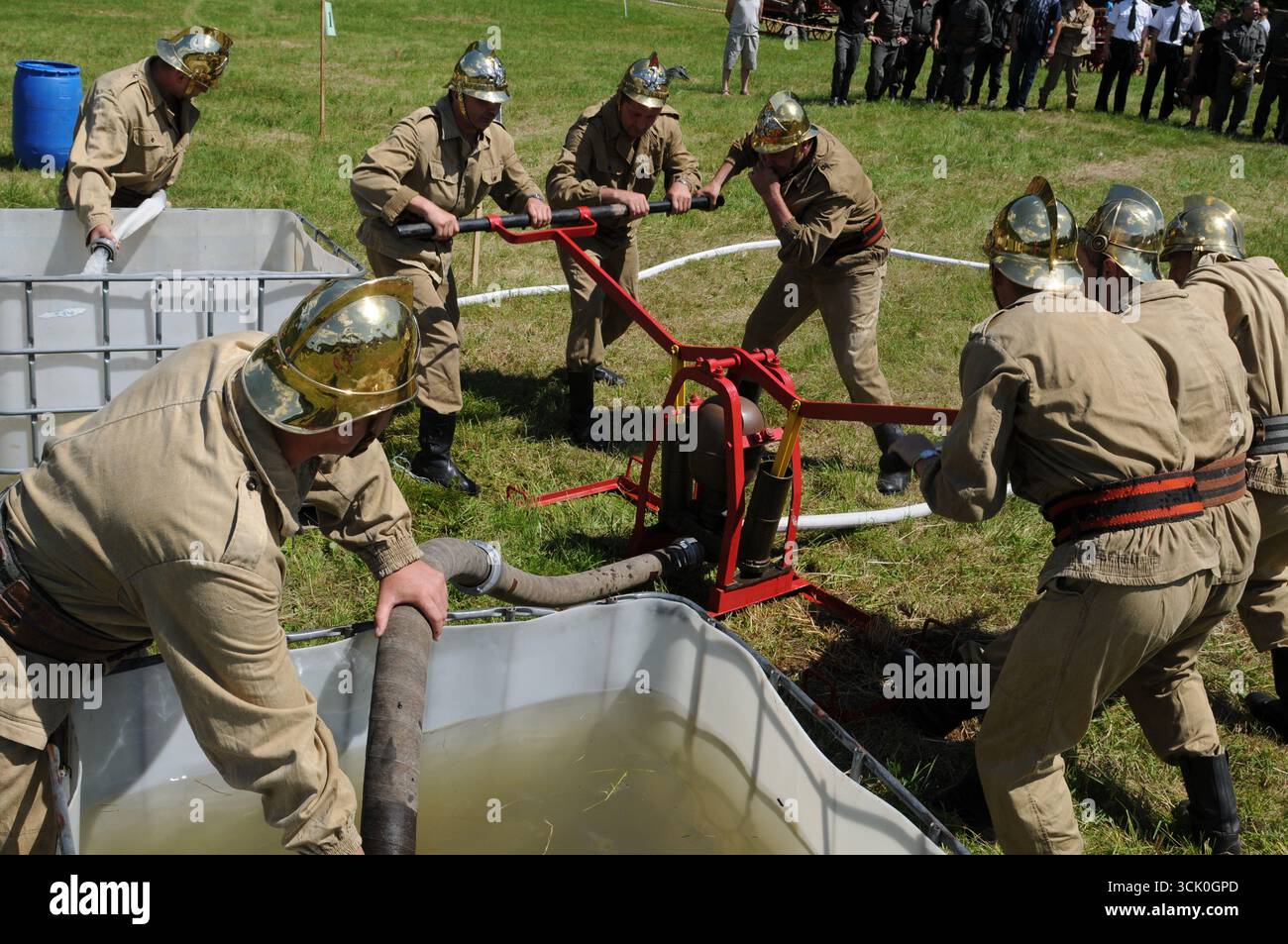 Fire brigade team operating a manual pump during historic firefighting ...