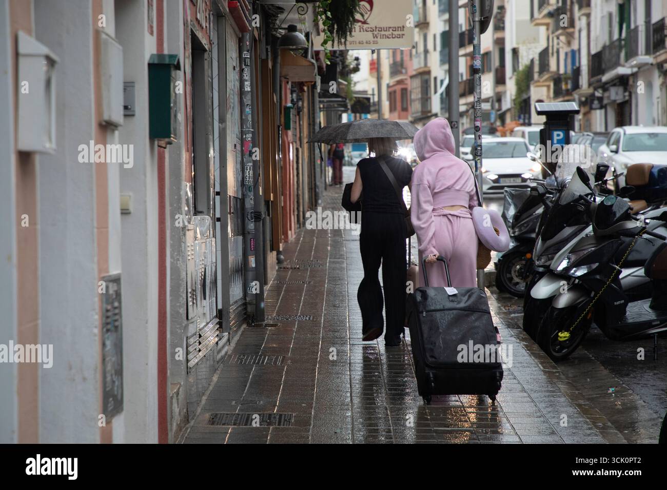 09 September 2025, Spain, Palma: People with umbrellas walk through ...
