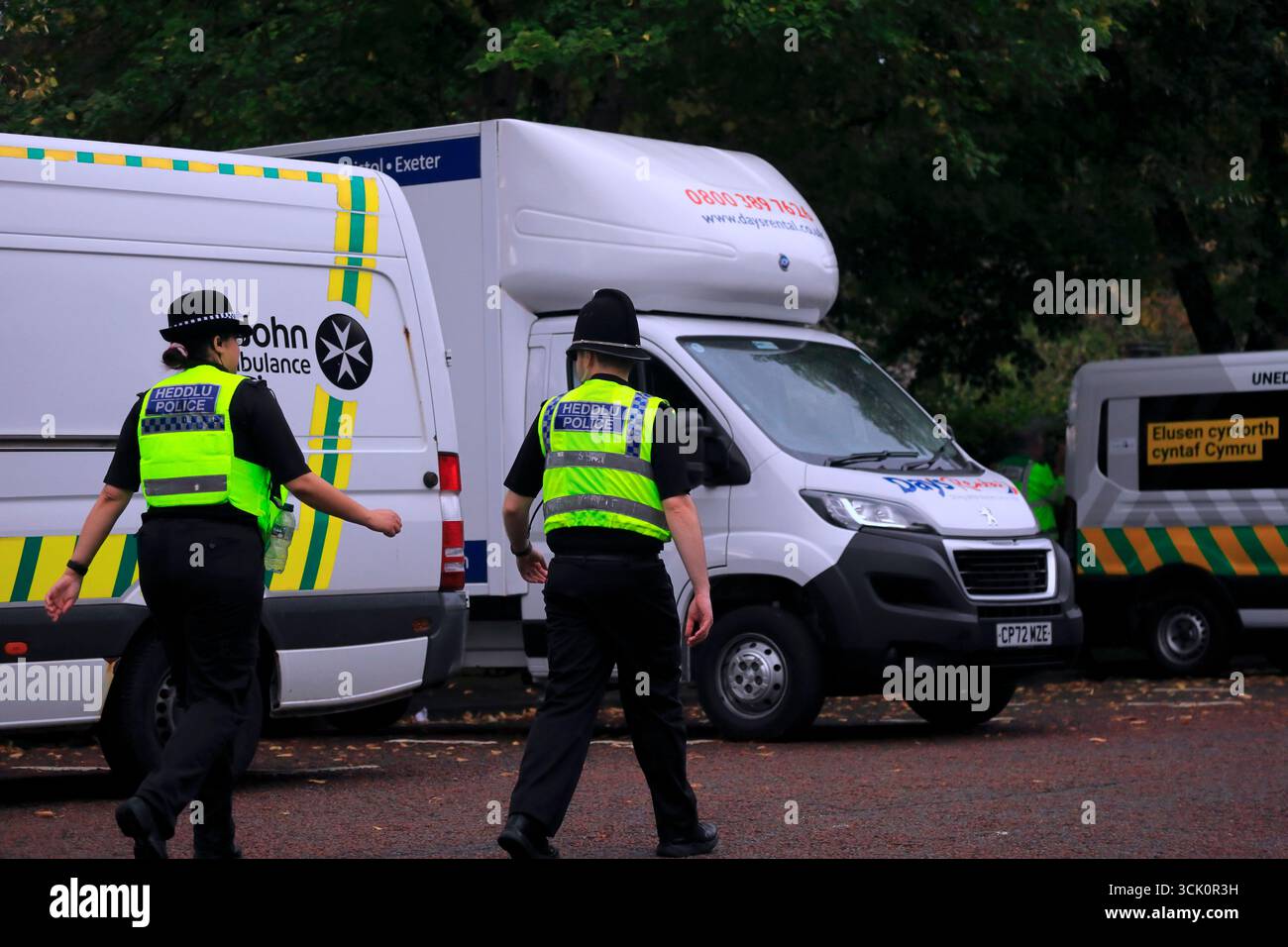 Two police constables - Heddly de Cymru - walk past St John's Ambulance ...