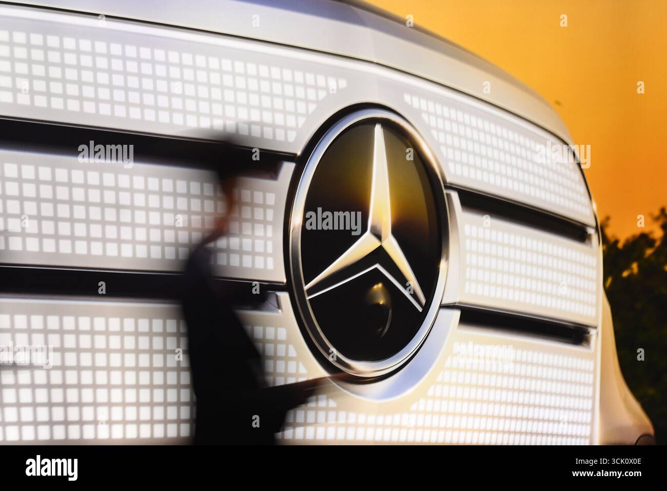 People walk past a large Mercedes-Benz poster featuring the new ...