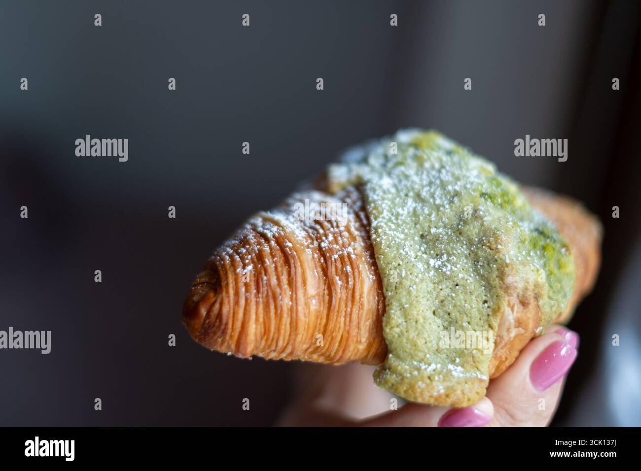 Croissant pastry features a vibrant green glaze and powdered sugar ...