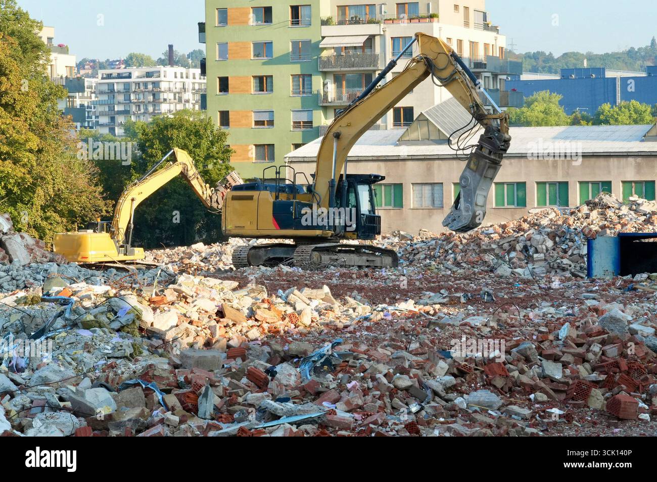Demolition of an old building with a large excavator in the foreground ...
