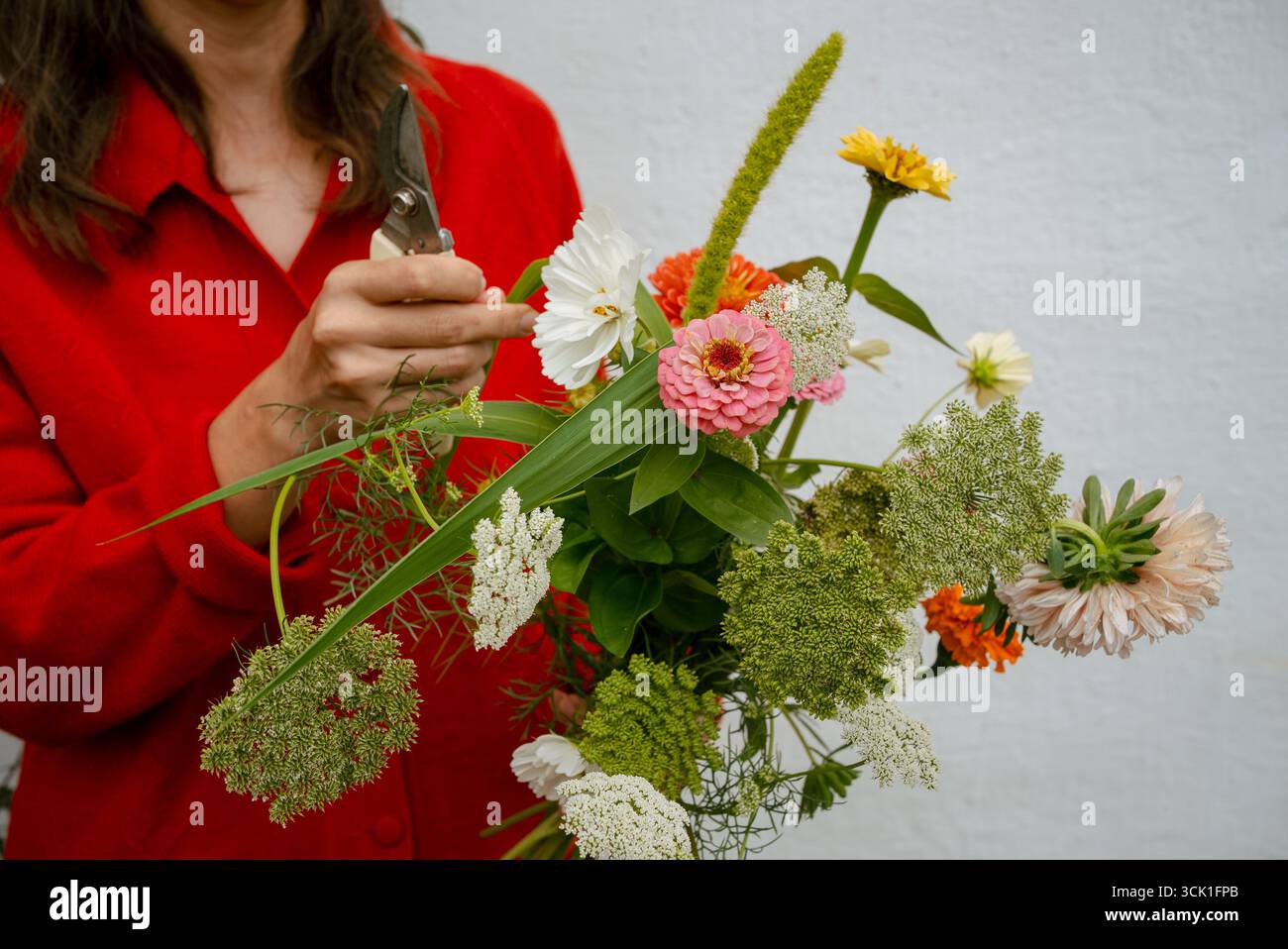 Florist wearing a red shirt carefully trimming stems and arranging a ...