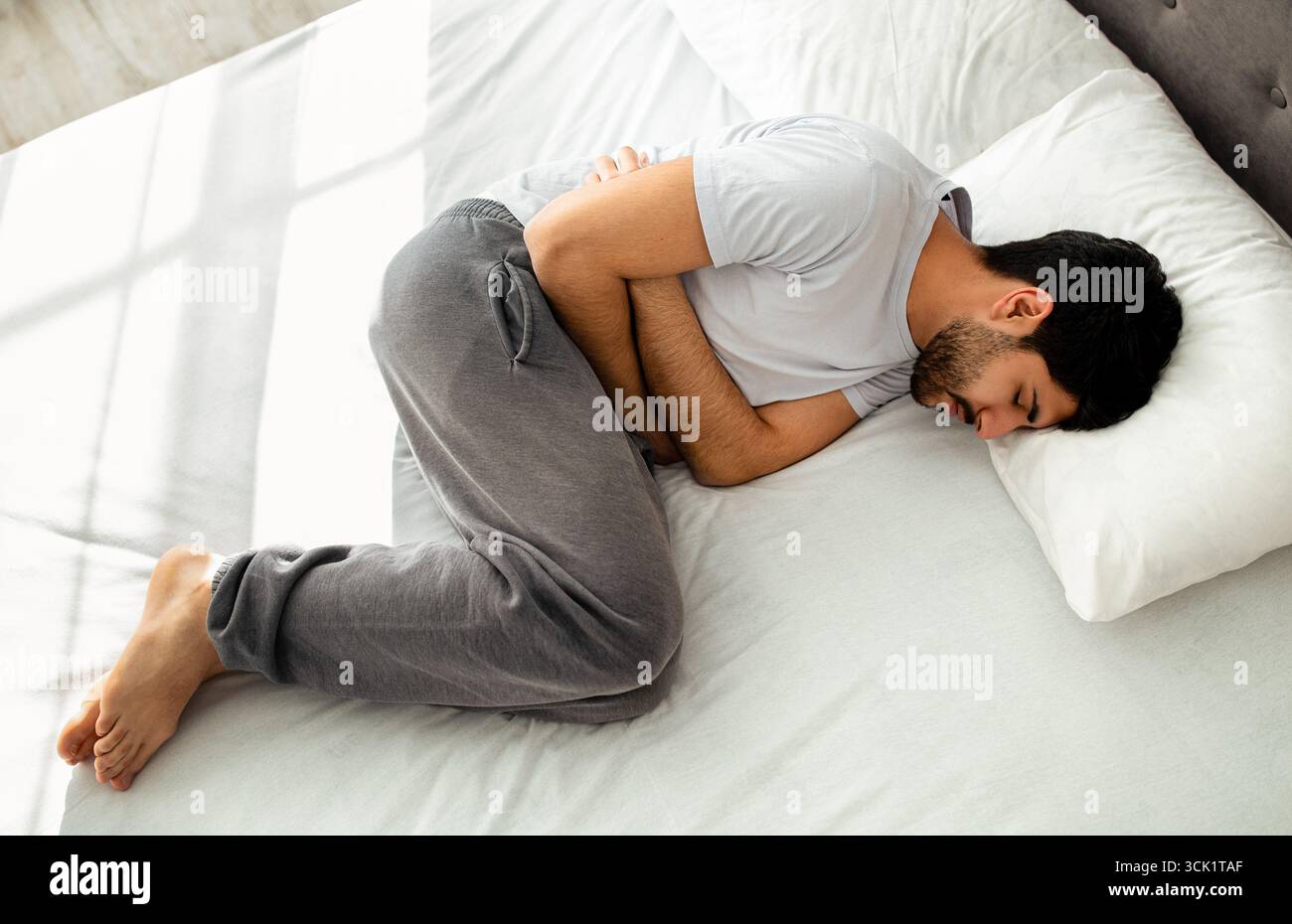 Stomachache. Young arab guy suffering abdominal pain touching aching ...