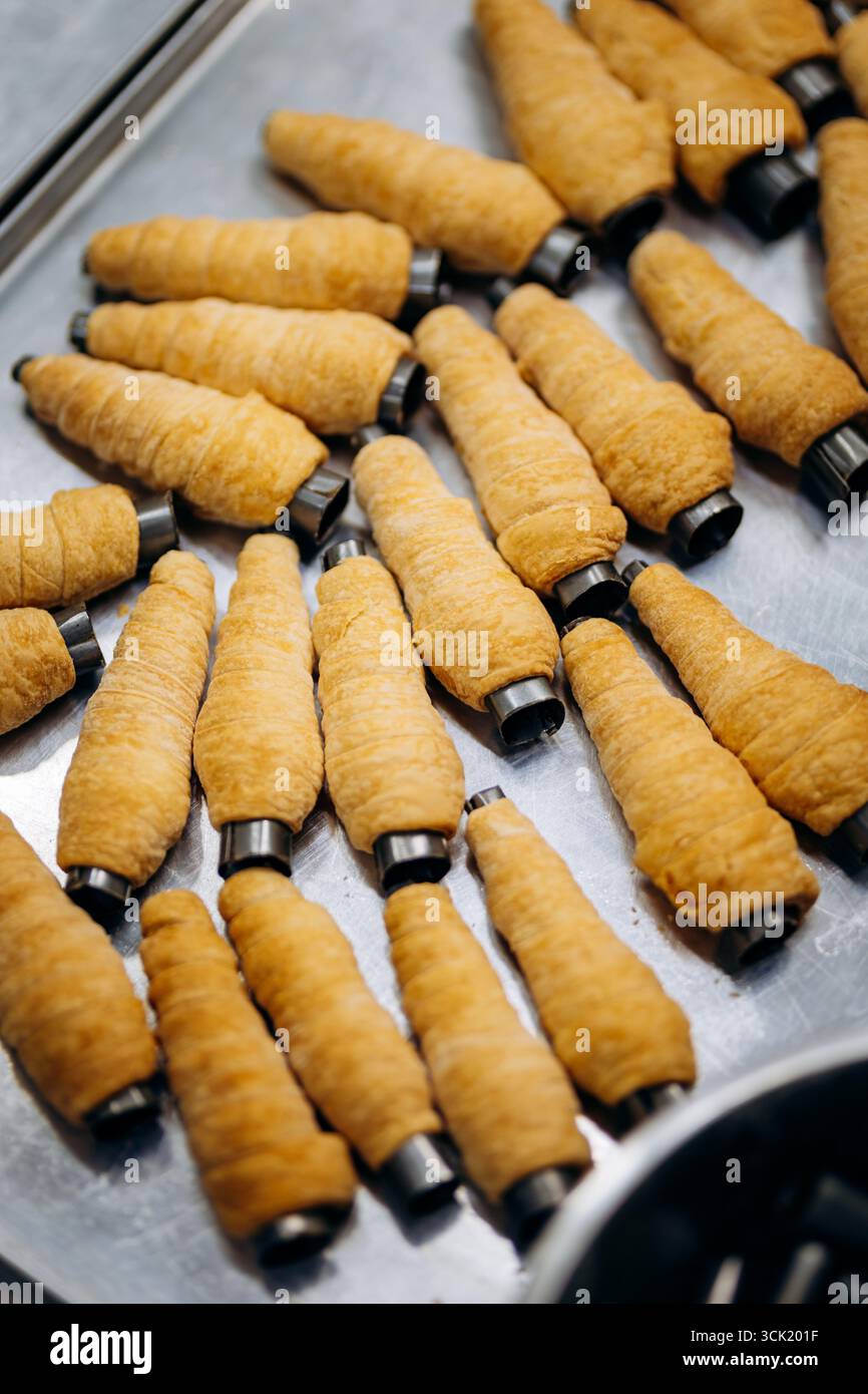 Unbaked puff pastry tubes on tray ready for cream filling in bakery ...