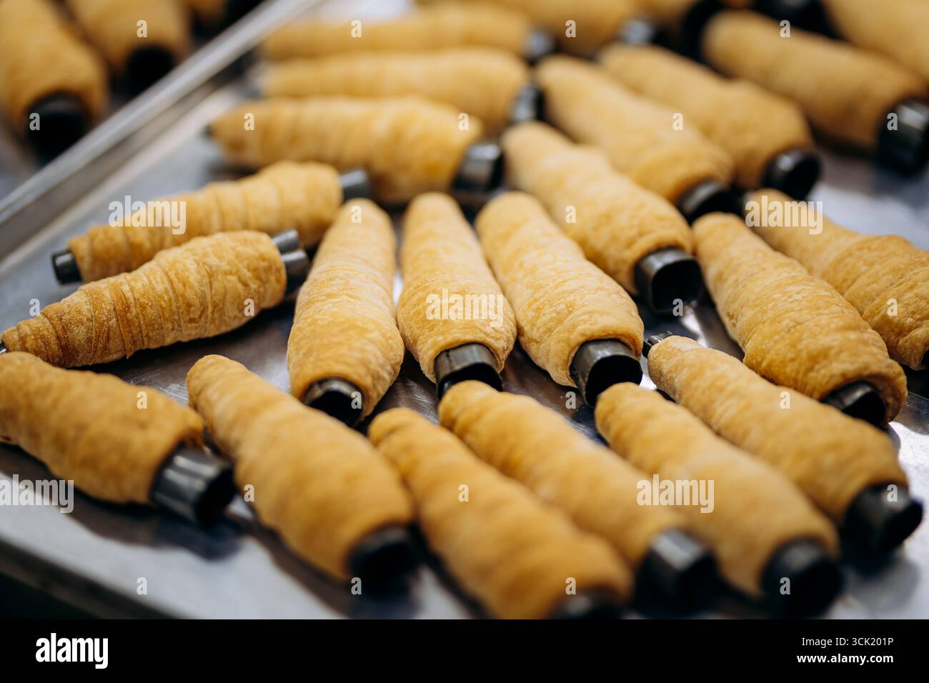Unbaked puff pastry tubes on tray ready for cream filling in bakery ...