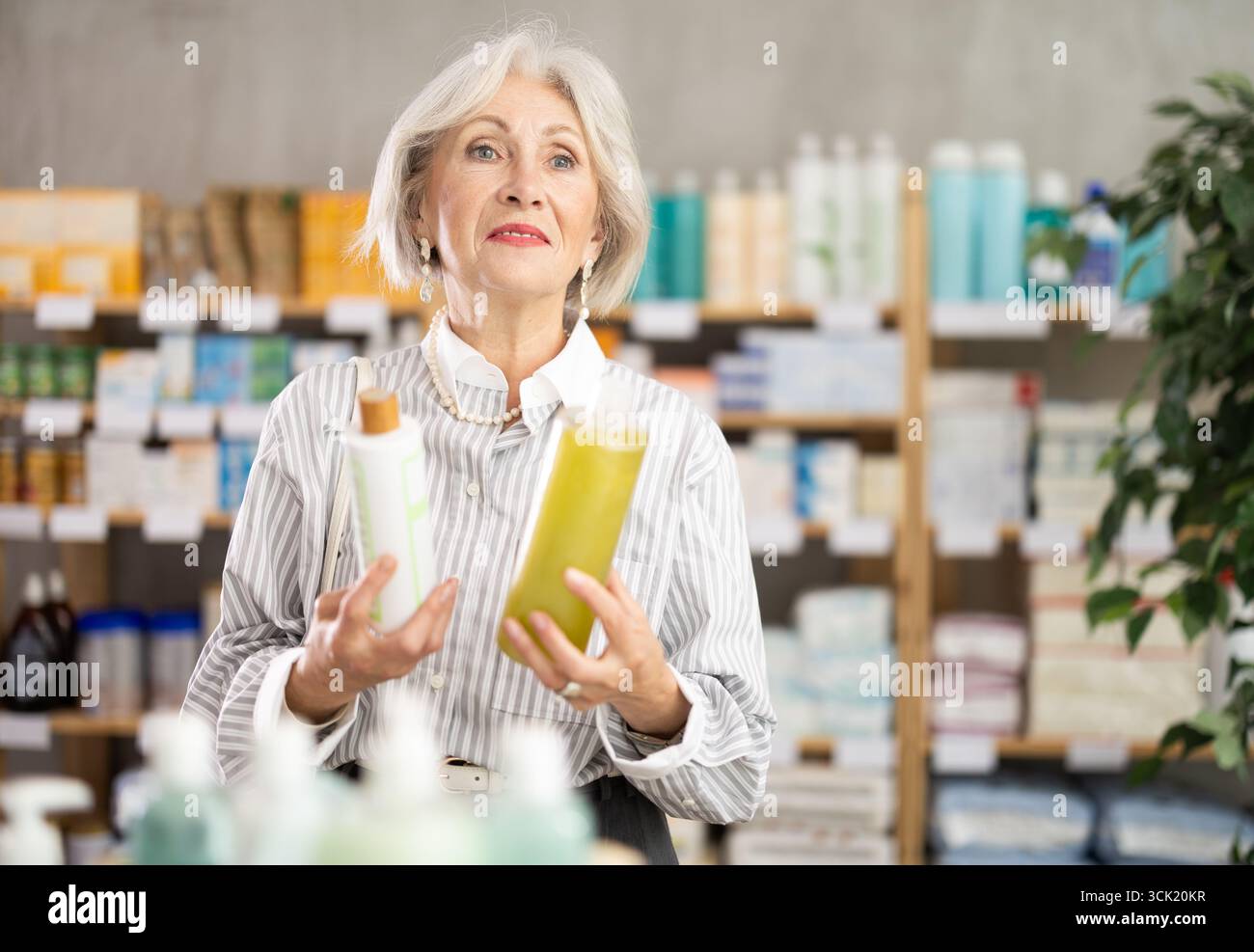 Elderly female shopper in summer clothes chooses medicated shampoo at ...