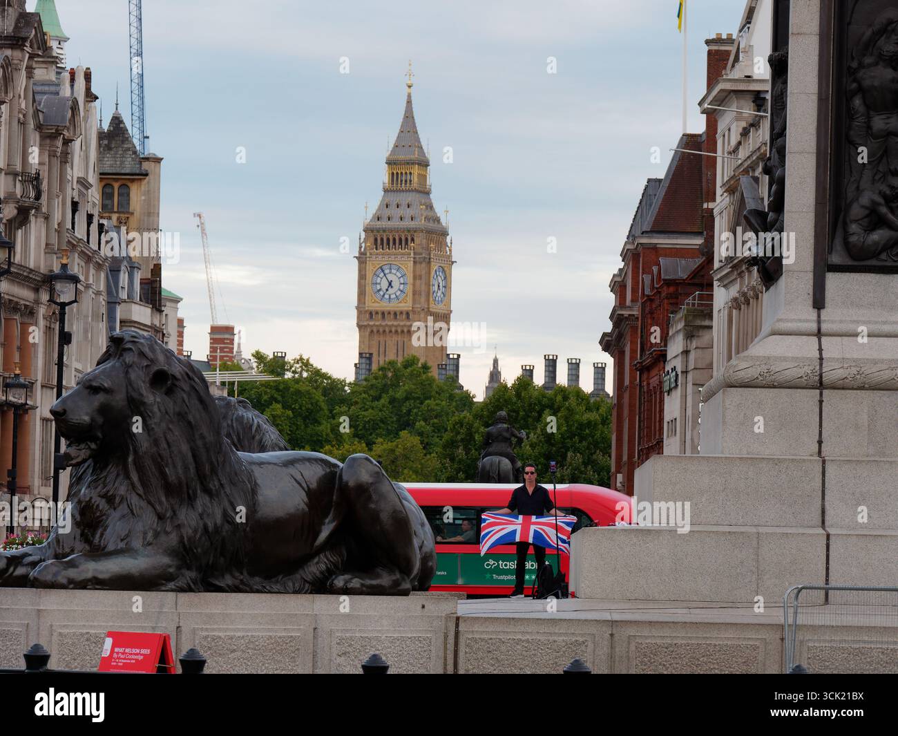Mans stands at the base of Nelsons Column in Trafalgar Square holding a ...