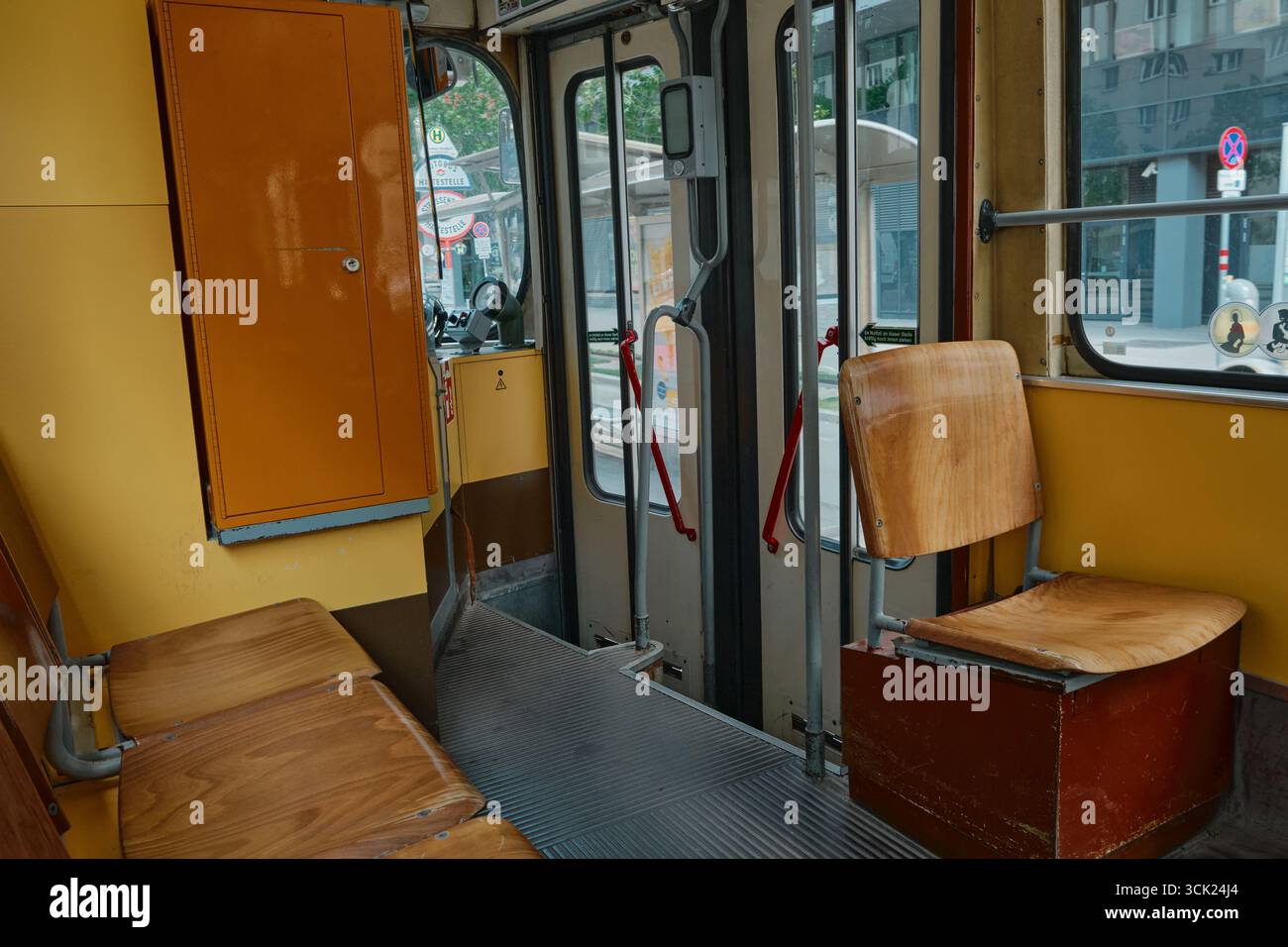 Inside view of a vintage city tram with wooden seats, yellow walls, and ...