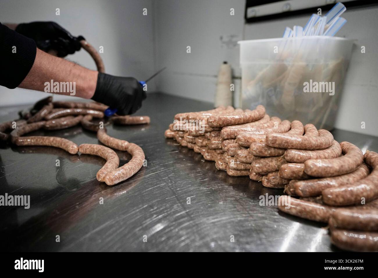 Dustin Price, a butcher at Deep Cuts butcher shop works on making maple ...