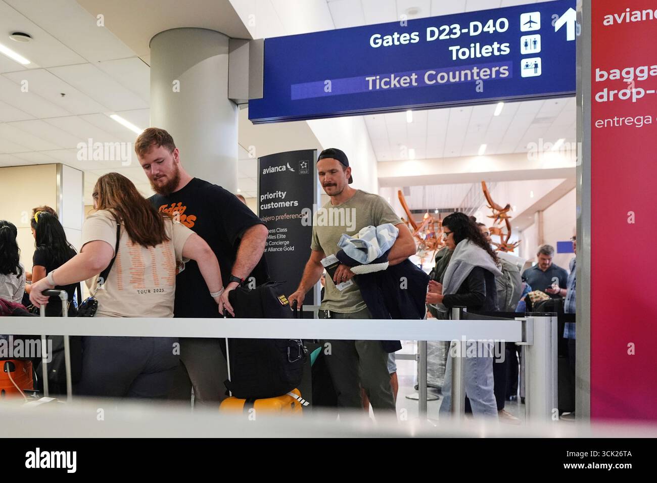 Travelers stand in line at a security checkpoint before boarding their ...
