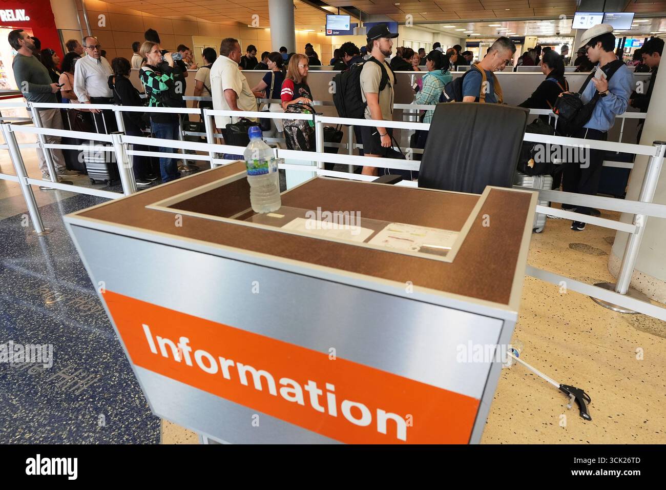 Travelers stand in line at a security checkpoint before boarding their ...
