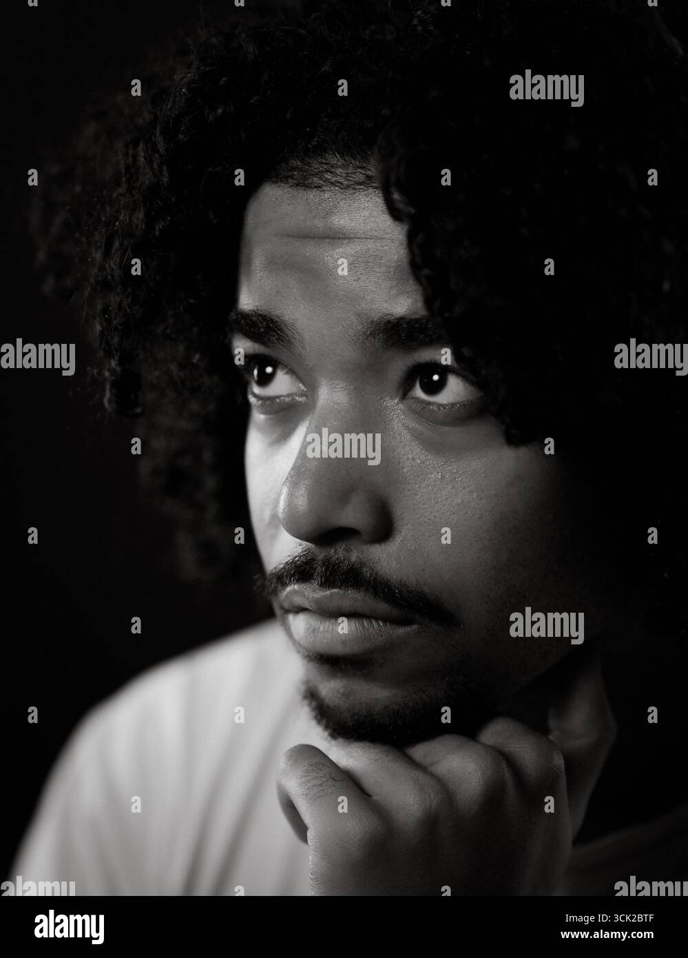 Black and white portrait of a thoughtful young man with afro hair and ...