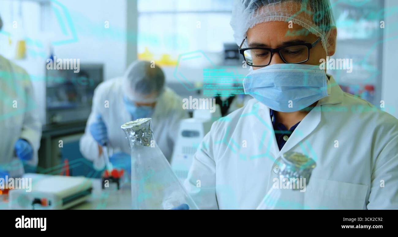 Mid adult scientist wearing lab coat holding Erlenmeyer flasks in lab ...