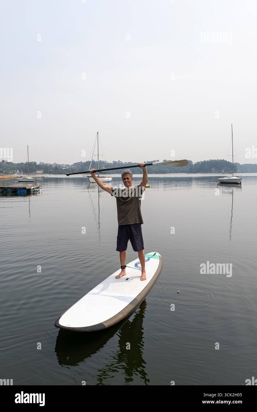 54 year old Brazilian on a standup paddleboard with the paddle over his ...