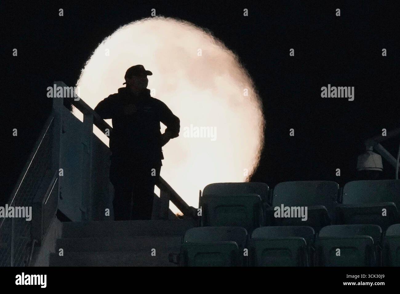A Dodger Stadium security guard stands in front of the moon during the ...