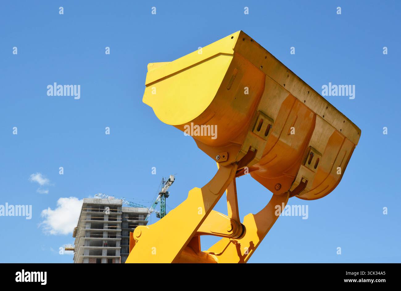 Bulldozer lifting bucket. Excavator bucket with high rise building ...
