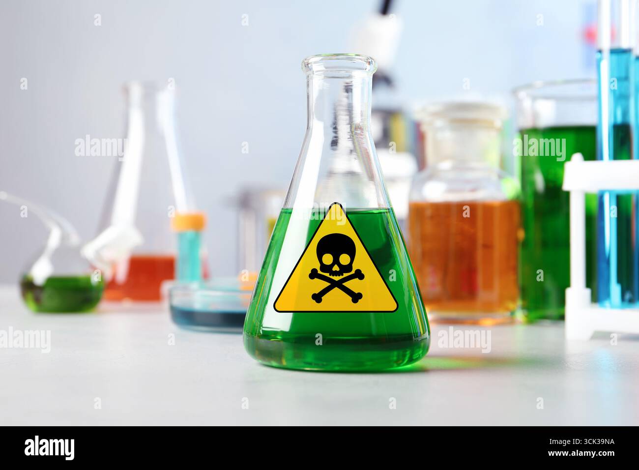Glass flask with Poison warning symbol and green liquid among other ...