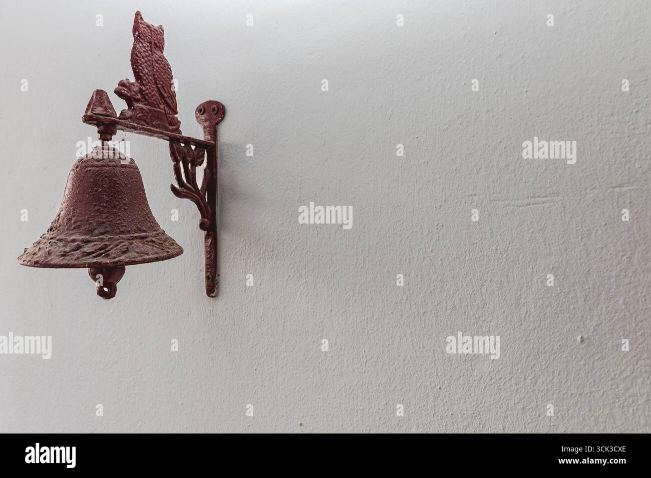 Vintage metal bell with rusty surface mounted on a textured wall ...