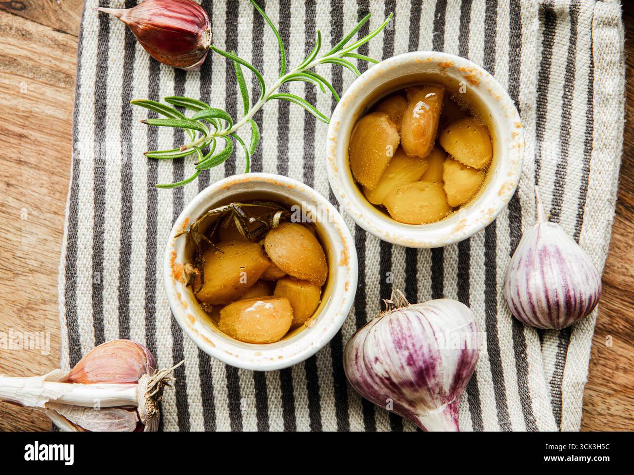 Above view of oven Roasted garlic confit inside small oven pots on ...